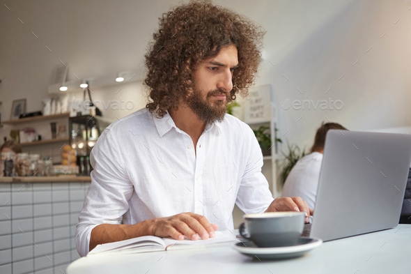 Severe male wearing white shirt checking emails online, using modern ...