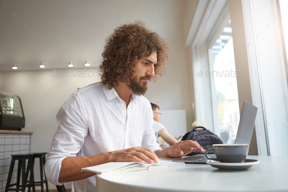 Severe male wearing white shirt checking emails online, using modern ...