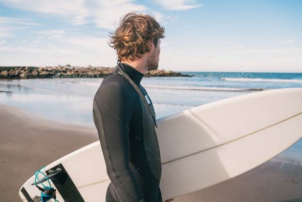 Surfer standing in the ocean with his surfboard. Stock Photo by megostudio
