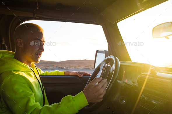 one young man driving his car alone and looking at the amazing sunset ...