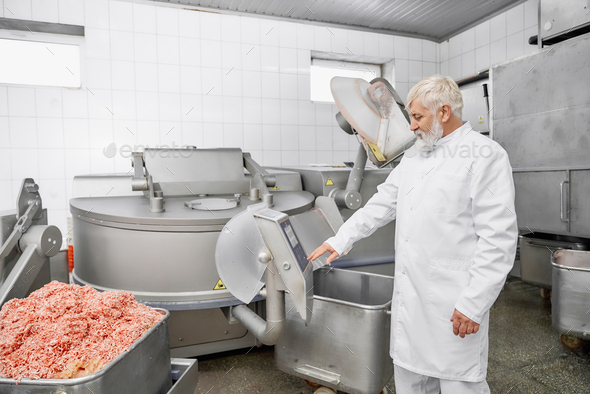 Professional butcher in uniform near equipment for meat Stock Photo by ...