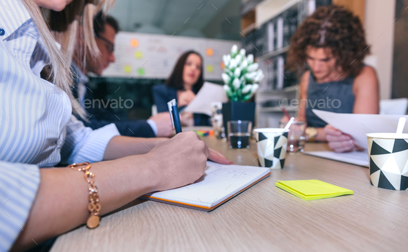Woman writing notes in a meeting with teamwork Stock Photo by davidpereiras