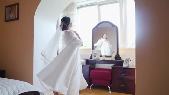 the bride takes off her wedding dress and posing near mirrow. Rotating ...