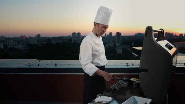 A professional Chef prepares a barbecue on the rooftop of a skyscraper ...