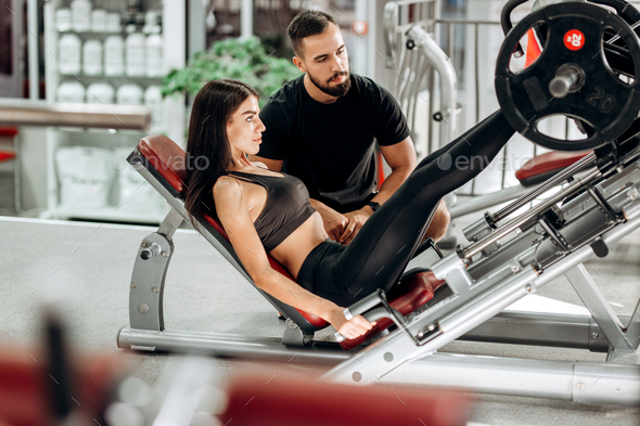 Slender girl dressed in black sport clothes is lifting weights with her ...