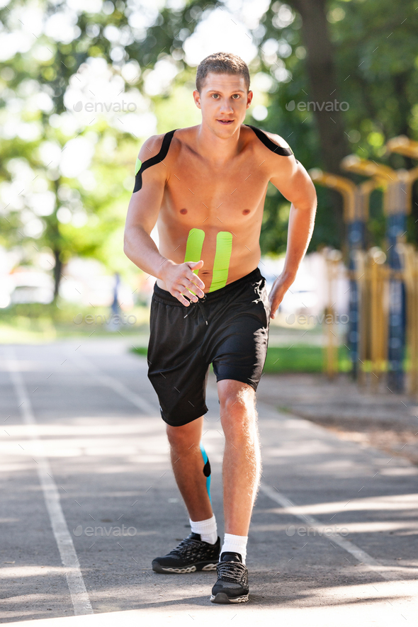 Male jogger with kinesiological taping running at stadium Stock Photo ...