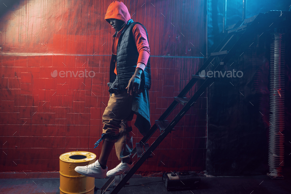 Stylish rapper in hoodie poses in grunge studio Stock Photo by NomadSoul1