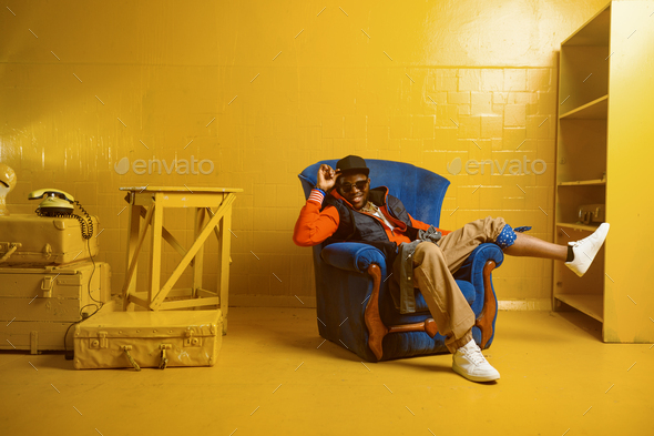 Rapper posing in chair in studio with yellow tones Stock Photo by ...