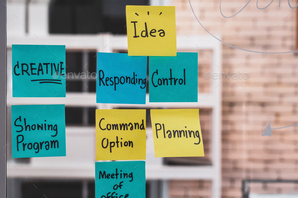 Various post it notes of business strategy wording over the glass wall ...