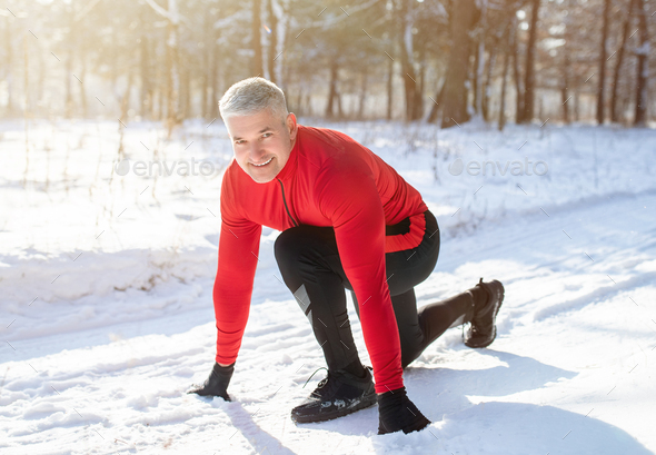 Senior man ready to run during winter training outside in cold snowy ...