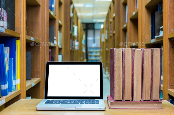 Laptop computer with old books on the wood table in library, Education ...