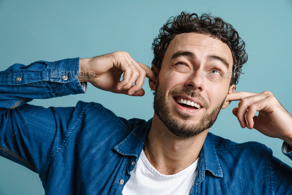 Cheerful handsome guy winking and plugging his ears Stock Photo by ...