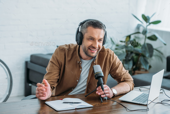 handsome radio host smiling while speaking in microphone in ...