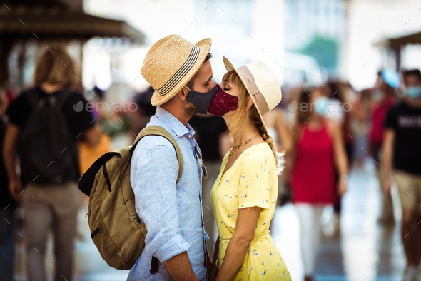 CCouple of lovers wearing protective face mask kissing each other in ...