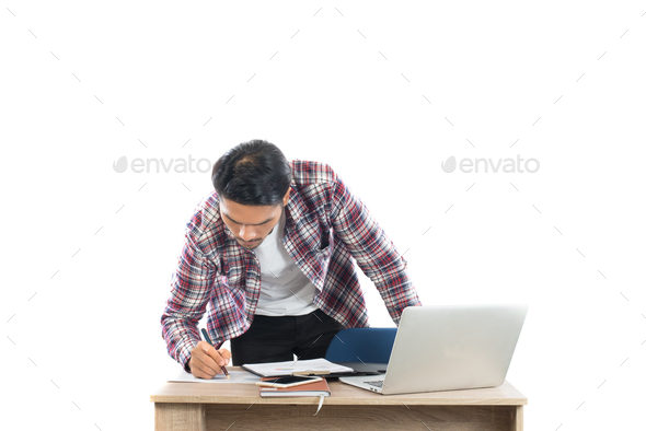 Young businessman and writing on his note sitting at his working place ...