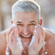 Happy senior man washing his face with snow, developing resistance to ...