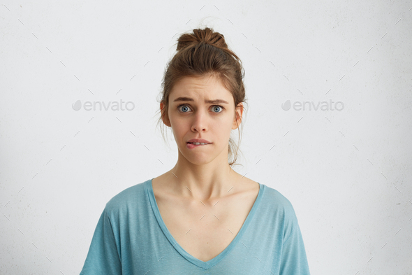 Young female having worried look biting her lower lip nervously looking ...