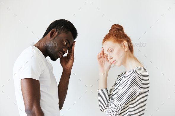Sideways portrait of couple in disappointed pose in white studio ...