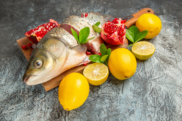 front view sliced fresh fish with lemon and pomegranates on light ...