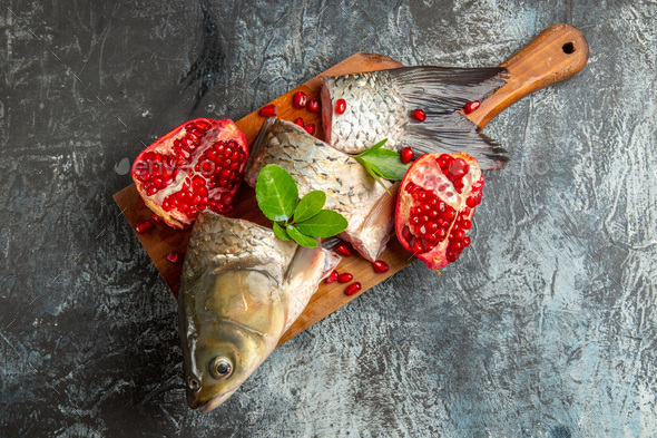 top view sliced fresh fish with pomegranates on dark background ocean ...