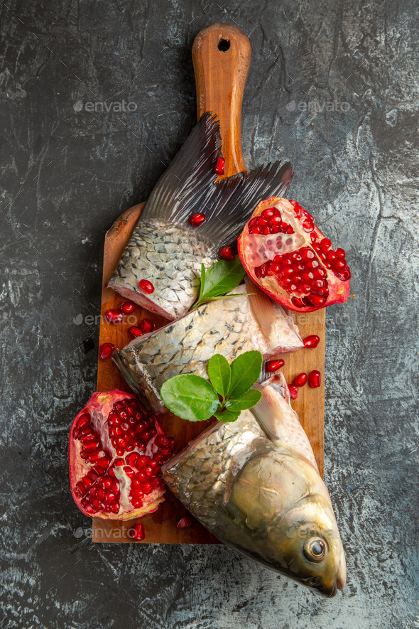 top view sliced fresh fish with pomegranates on a dark background ocean ...
