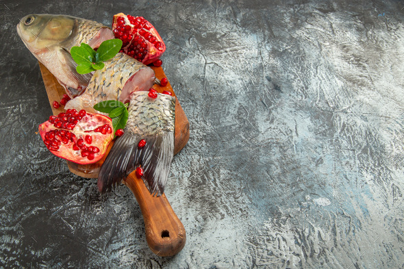 front view sliced fresh fish with pomegranates on light-dark background ...