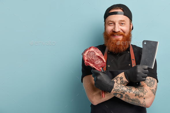 Image of satisfied red haired butcher smiles happily, involved in ...