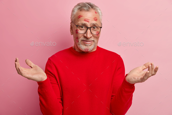 Indifferent mature man with grey hair and beard, shruggs shoulders in ...