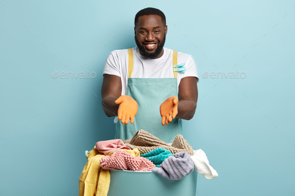 Cheerful householder with dark skin demonstrates washed clean garment ...