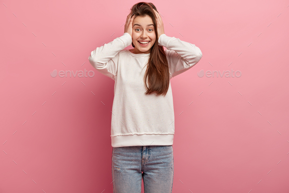 Joyous European woman with cheerful facial expression, keeps both hands ...