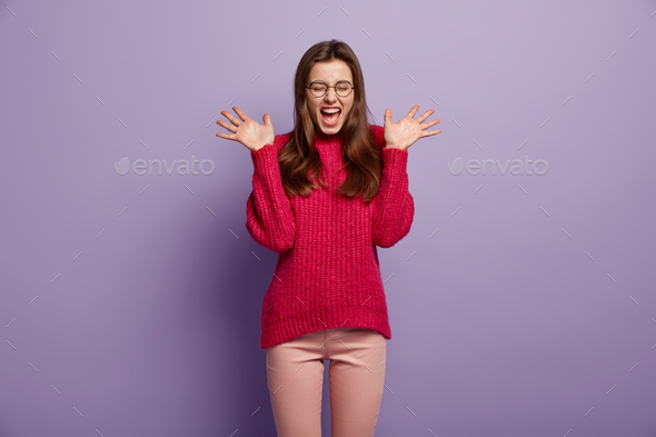 Shot of overjoyed happy young female model spreads palms near face ...