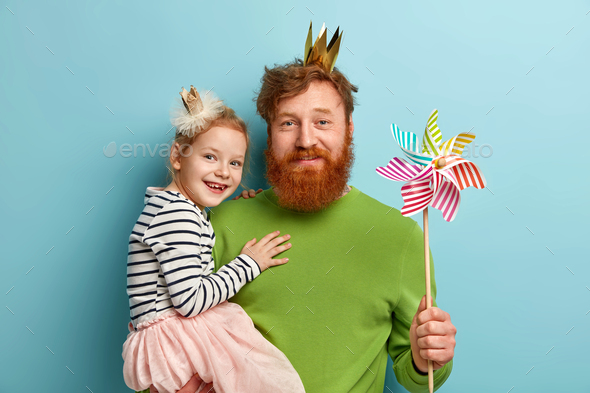 Happy ginger family of father and daughter wear party accessories, hold ...