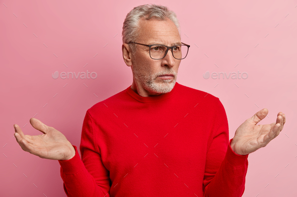 Puzzled clueless old man with grey beard and hair, spreads hands in ...