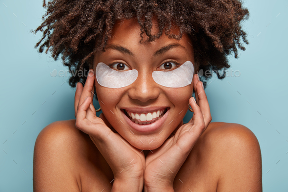 Happy African American woman has anti wrinkle patches under eyes, wants ...
