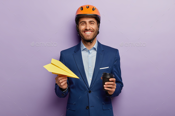 Positive male trader wears helmet, elegant business clothes, holds ...