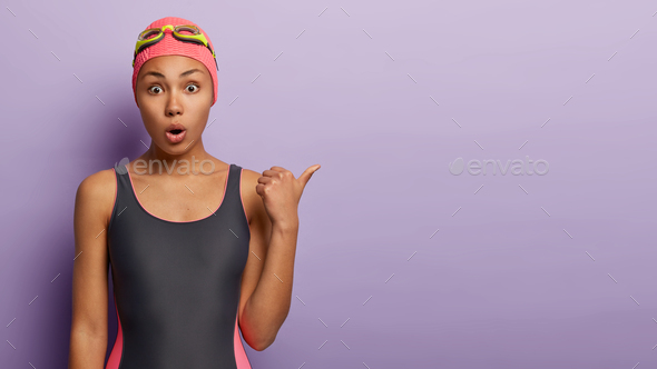 Half length shot of stupefied healthy woman with dark skin, dressed in ...