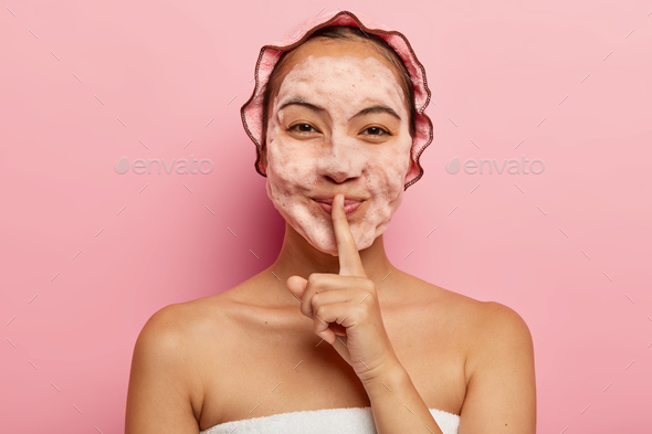 Horizontal view of pretty Asian lady with foam on face, cleans from ...