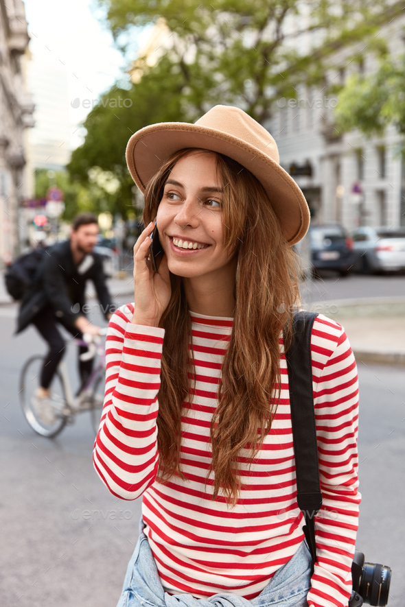 Talkative young female has phone conversation with friend, looks away ...