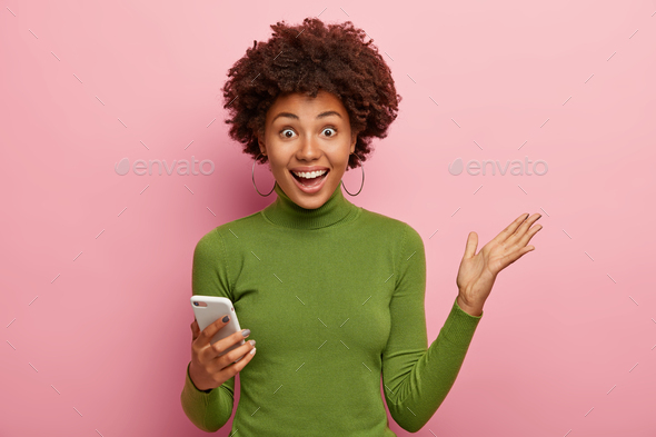 Emotional dark skinned woman has overjoyed face expression, gestures ...