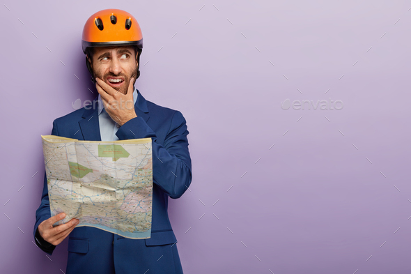 Photo of puzzled dissatisfied male engineer worker holds chin, holds ...