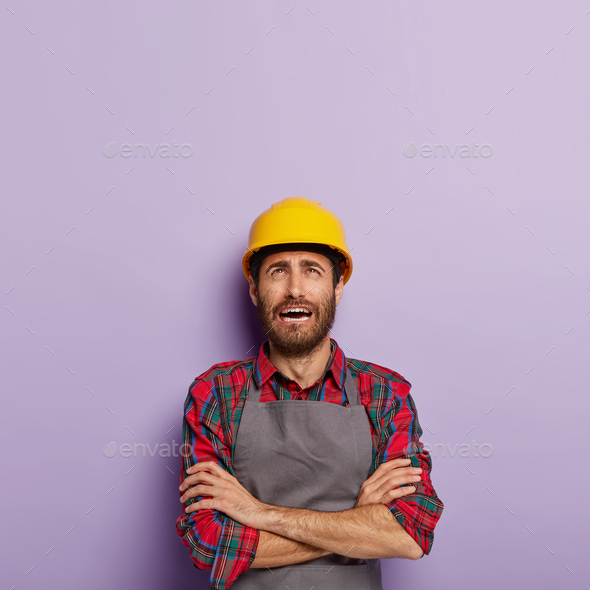 Stressful dissatisfied male engineer keeps arms folded has miserable ...