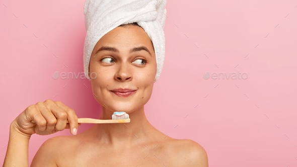 Close up shot of calm relaxed woman holds toothbrush, cleans teeth ...