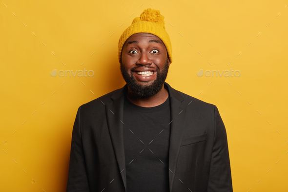 Positive funny youngster with black skin, has bright appealing smile ...