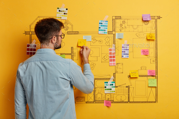 Back view of bearded male designer or architect presents renovation ...