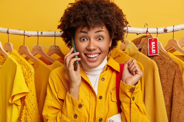 Joyful curly woman with overjoyed face expression, broad smile, raises ...