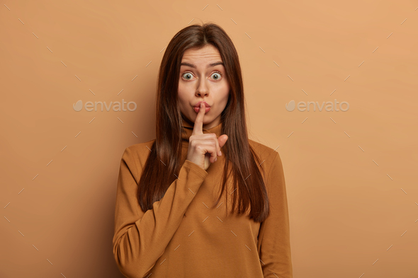 Brunette European Woman Keeps Index Finger On Lips Make Hush Gesture