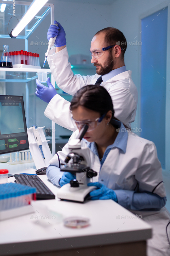 Scientist examining blood sample looking under microscope Stock Photo ...