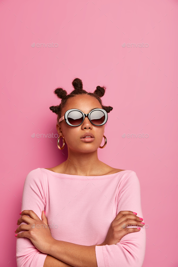 Self confident dark skinned woman keeps arms folded, stands in ...