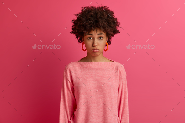 Young distressed curly woman has sad expression, pity face, feels ...