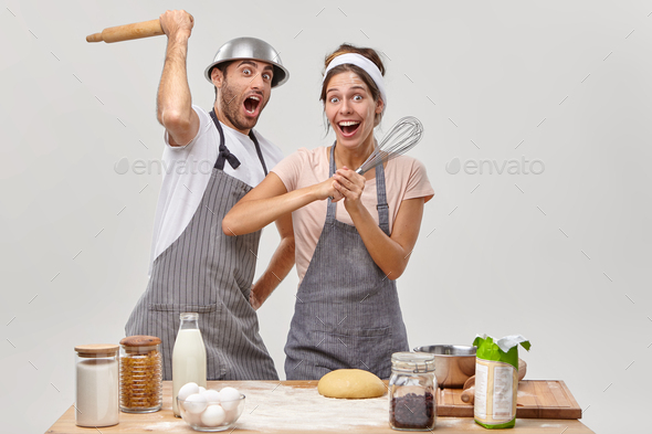 Joyful family couple have fight with cooking utensils, have fun during ...